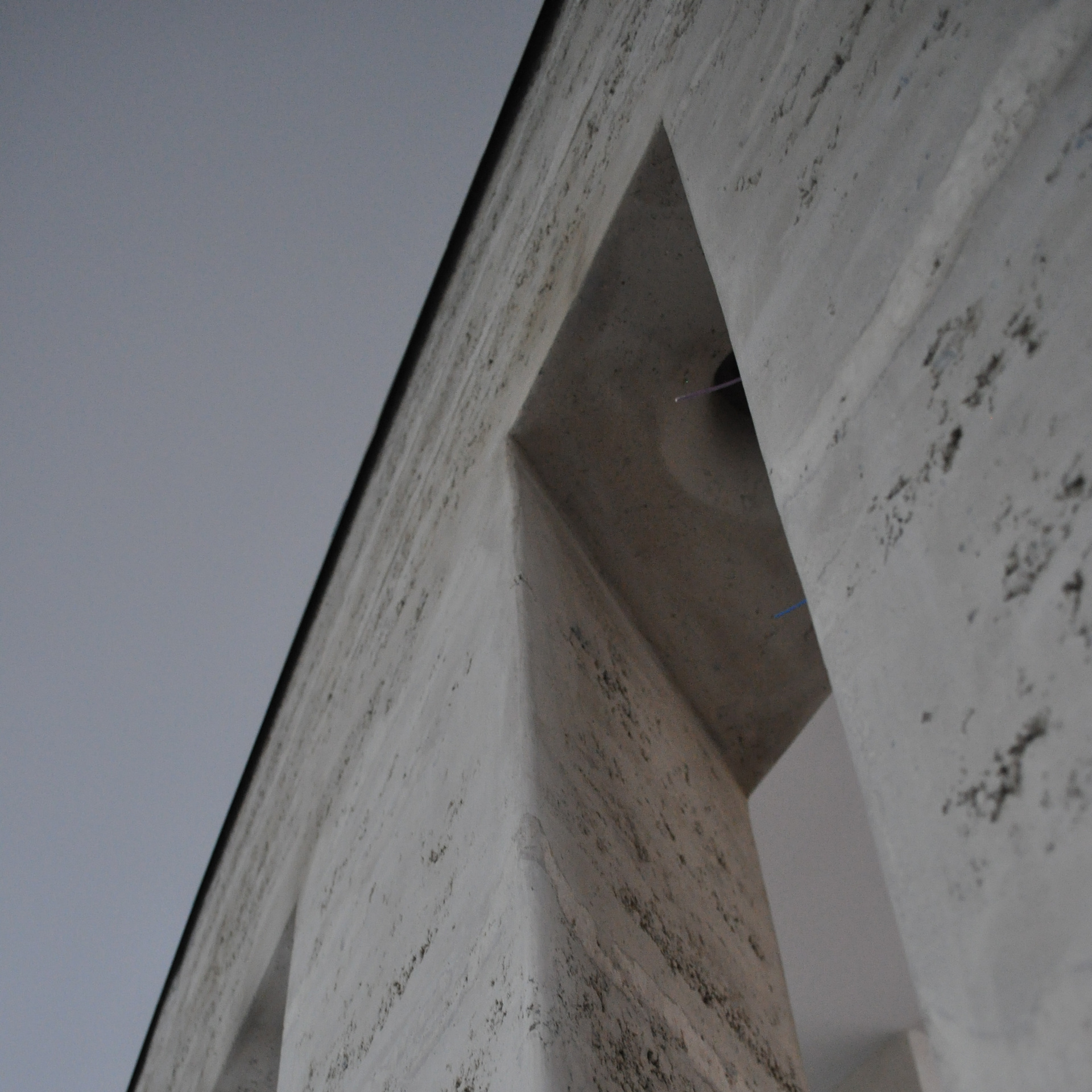 Un mur en pisé intérieur avec des ouvertures en biais et des spots ...