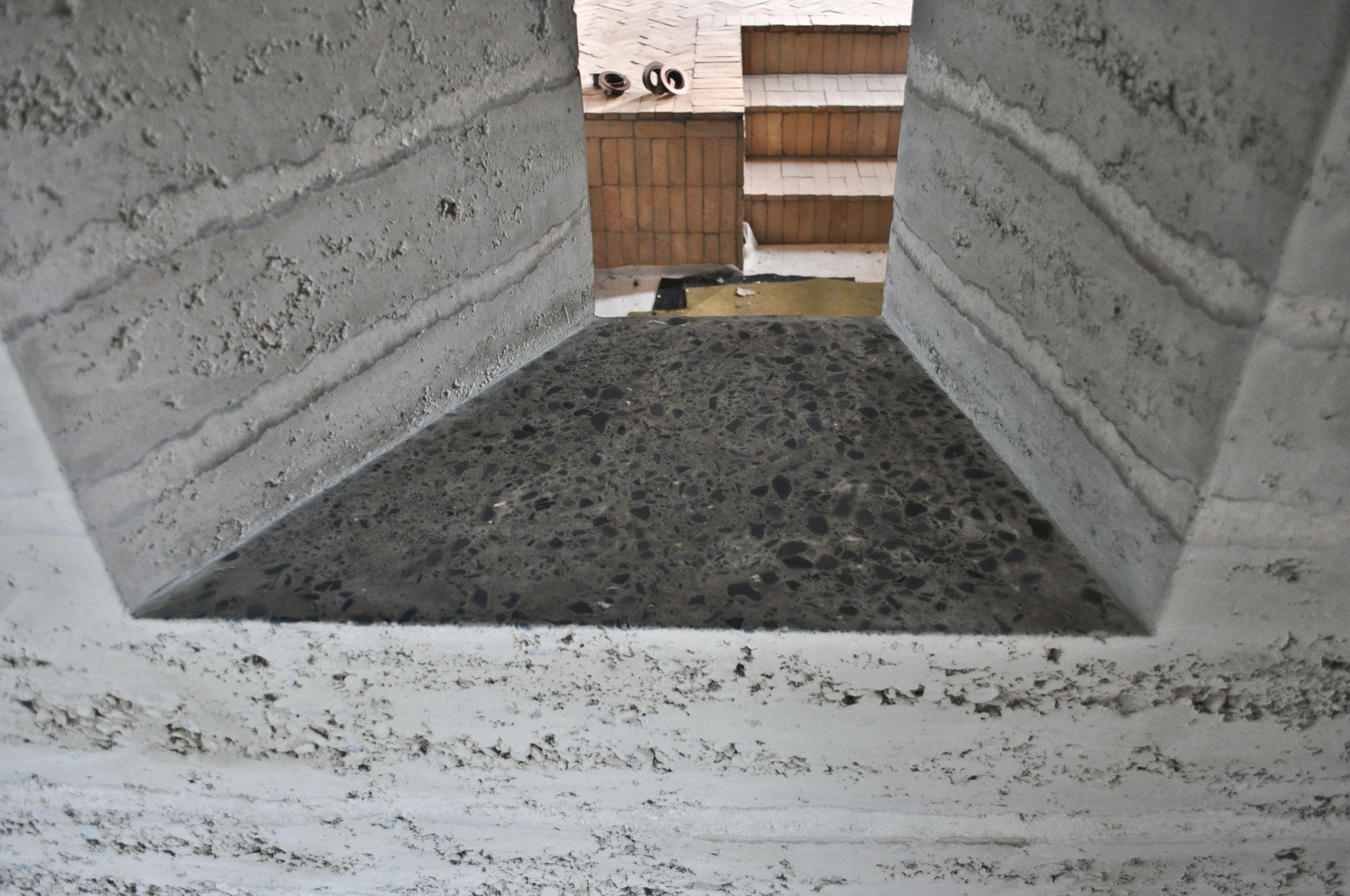 Un mur en pisé intérieur avec des ouvertures en biais et des spots ...